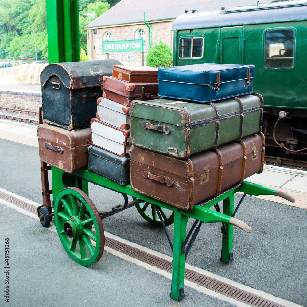 Luggage on porter's trolley on railway platform. Suit cases and trunks ...