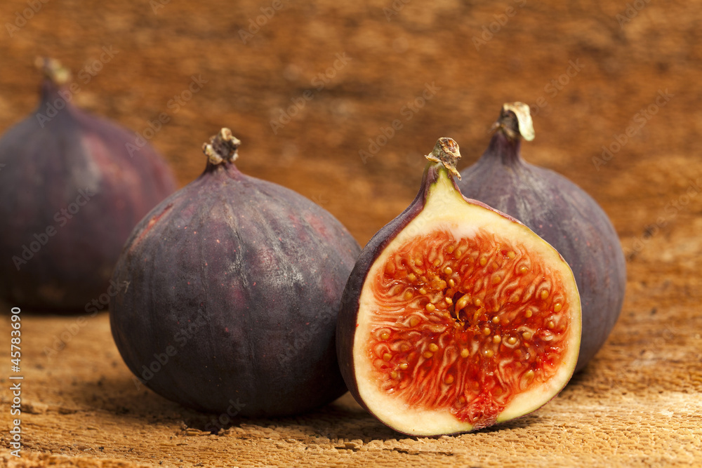 Two whole and a halved fig fruits on bark as background Stock Photo ...