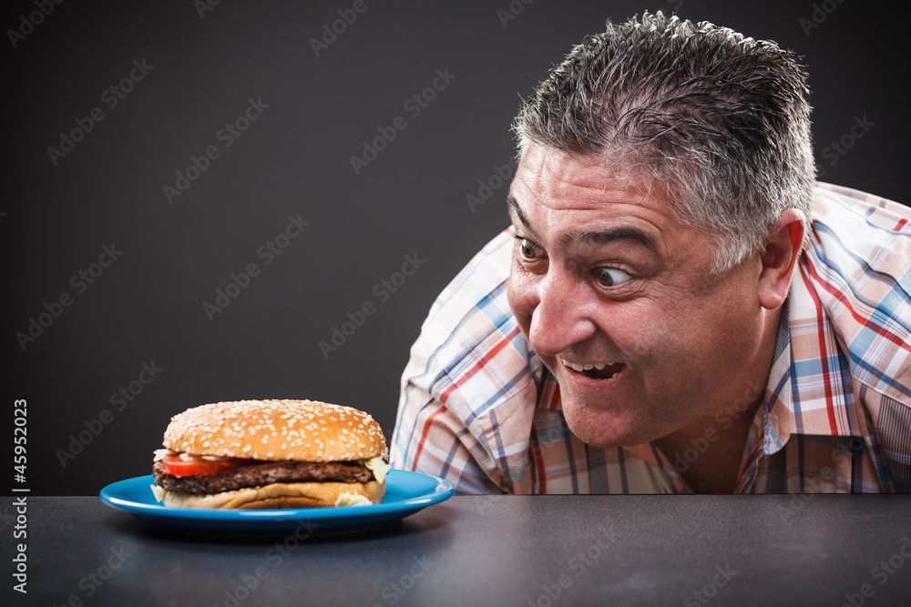 Greedy man looking at burger Stock Photo | Adobe Stock