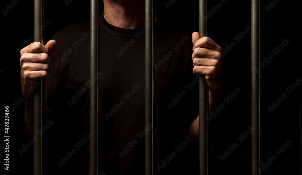 prisoner behind bars Stock Photo | Adobe Stock