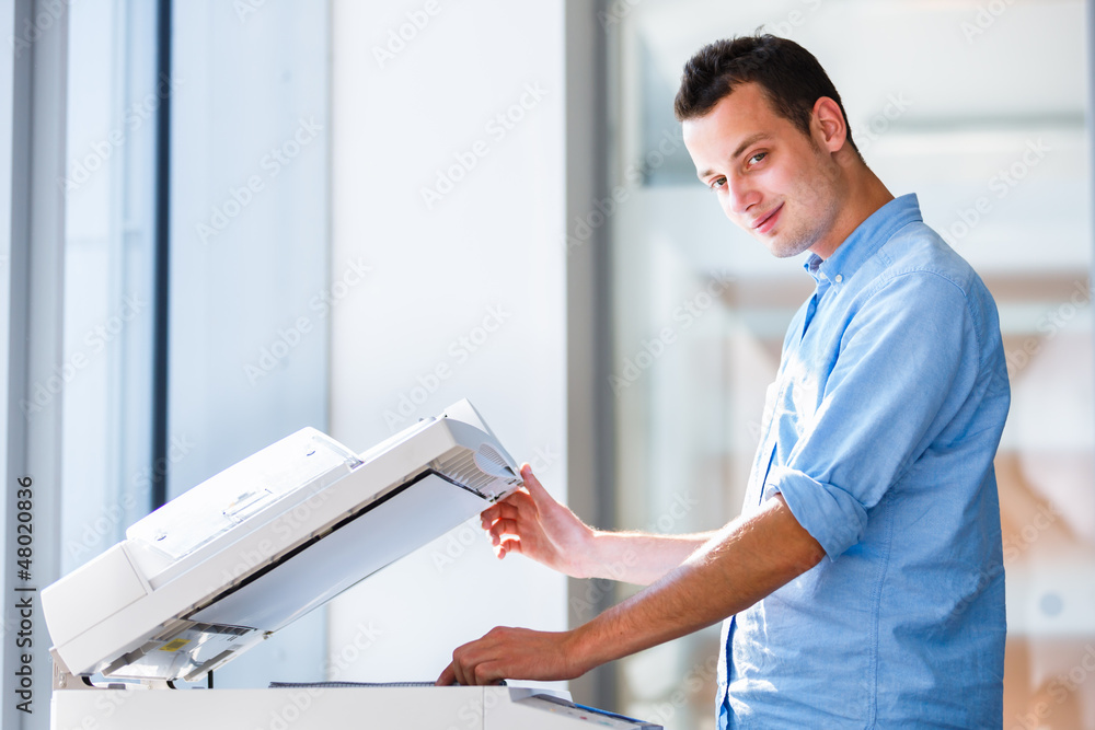 Handsome young man using a copy machine Stock-Foto | Adobe Stock