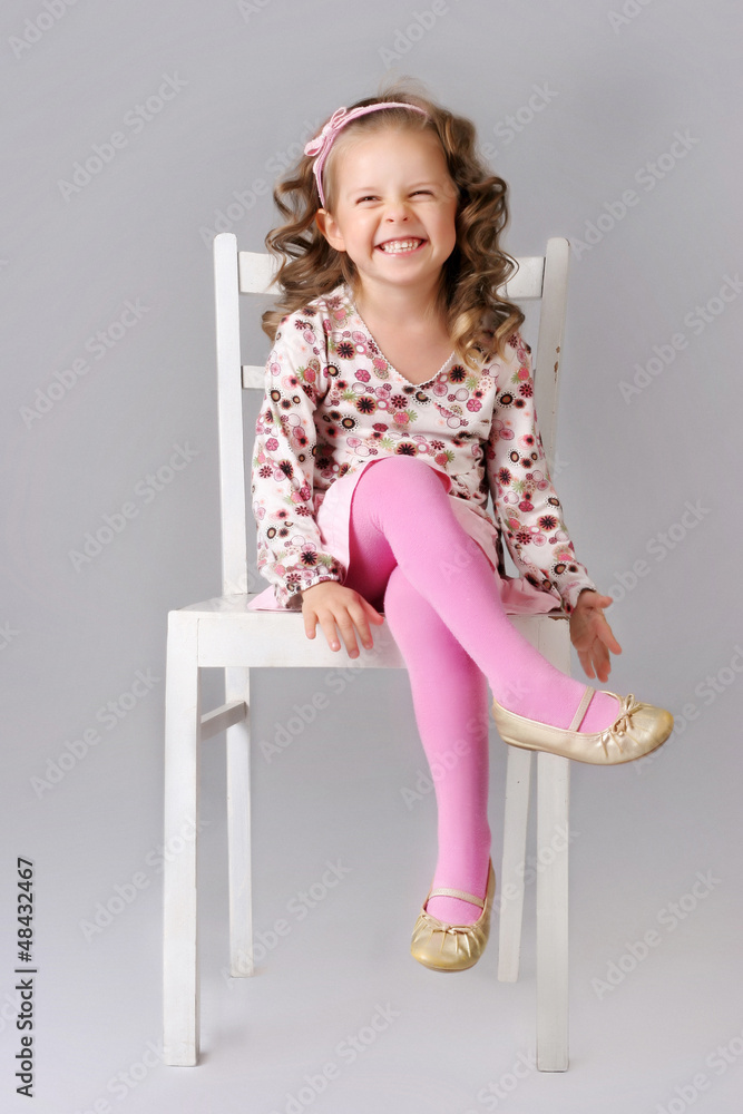 Cute little child sitting on the chair and smiling Stock Photo | Adobe ...