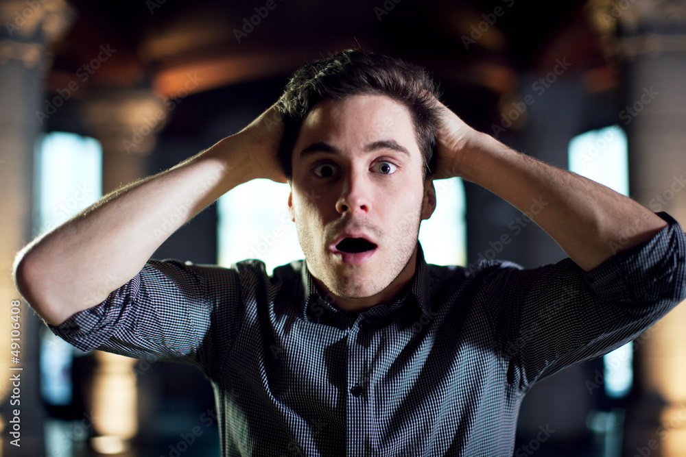 Homme choqué tenant sa tête avec ses mains Photos | Adobe Stock