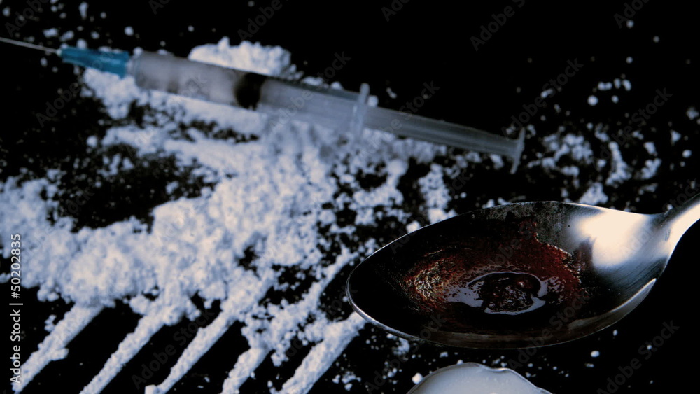 Syringe falling on white drug while drug is cooking on spoon Stock ...