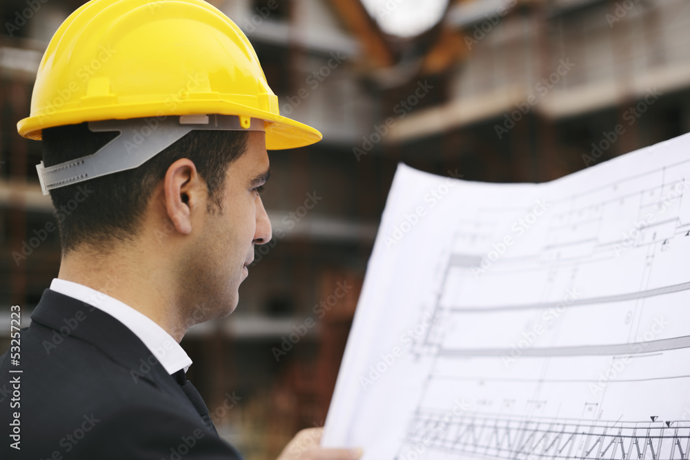 Architect in construction site looking at building plans Stock Photo ...