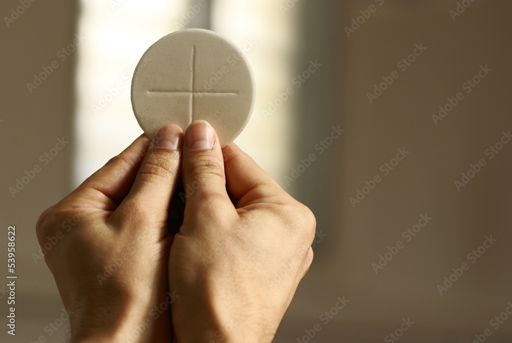 Hands holding communion wafer at church interior. Stock Photo | Adobe Stock