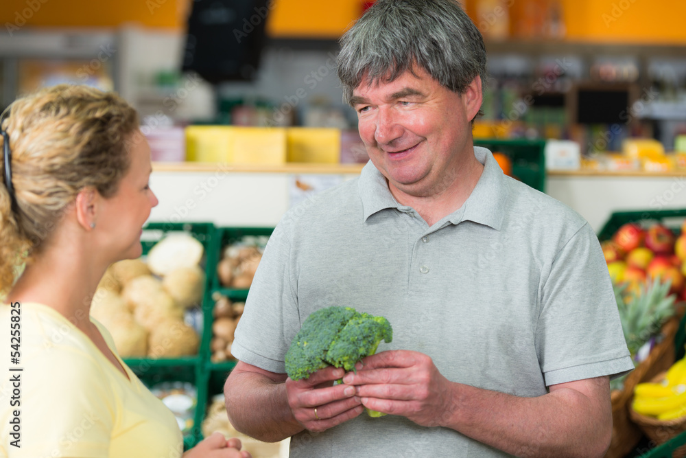 verkäufer berät kundin beim gemüse Stock-Foto | Adobe Stock