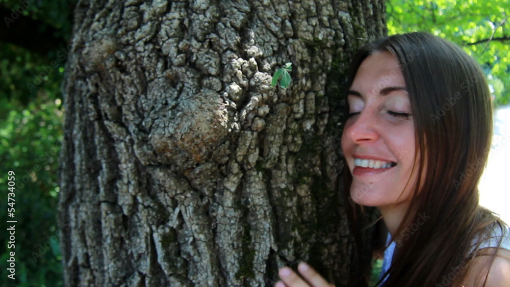 Happy beautiful girl hugging big tree in park Stock Video | Adobe Stock