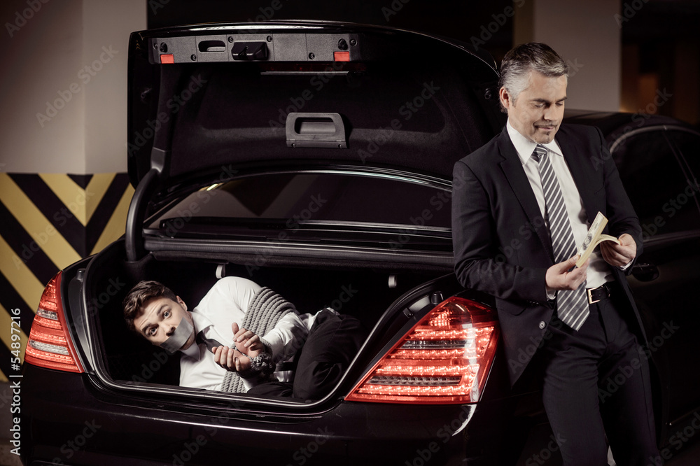 Kidnapped man. Tied up businessman lying in the car trunk and lo Stock ...