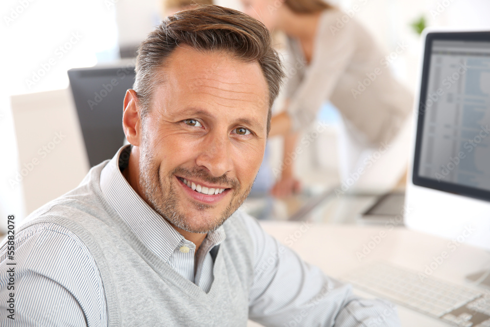 Cheerful man sitting in office and working on desktop Stock Photo ...
