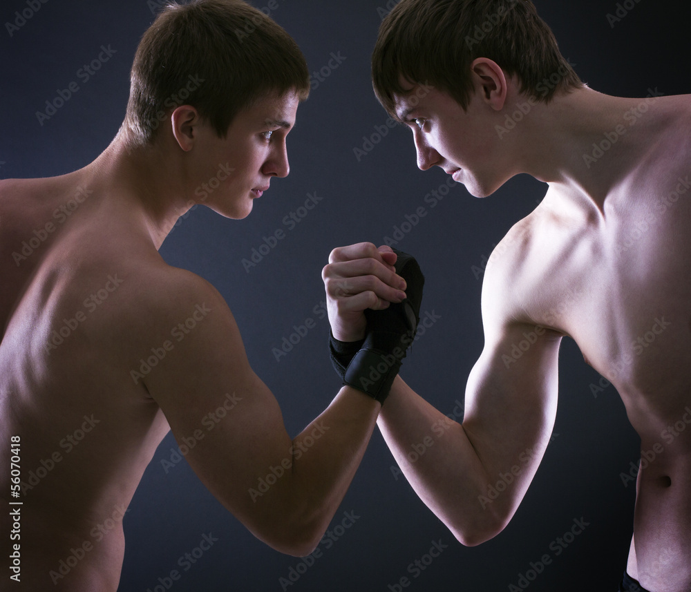 Two muscular men fighting on a dark background. Stock Photo | Adobe Stock