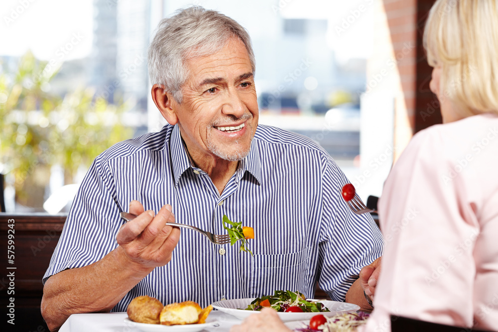 Senior man talking to woman while eating Stock Photo | Adobe Stock