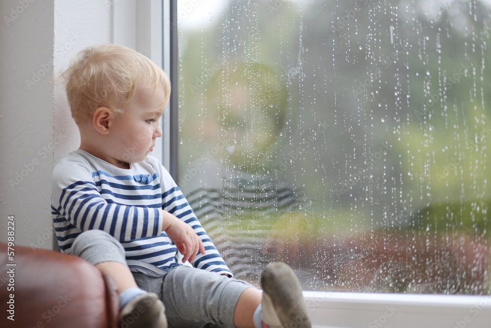 Cute baby girl looking outside through the window during rain Stock ...