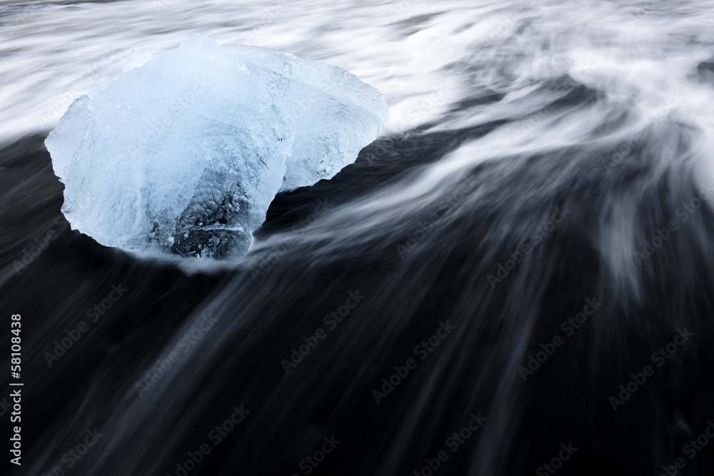 Ice block on a beach with lava stones and water floating over. Stock ...