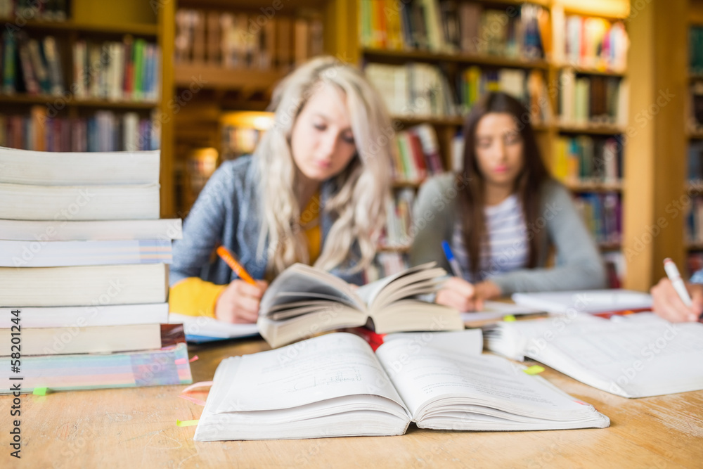 Students writing notes with stack of books at library desk Stock Photo ...