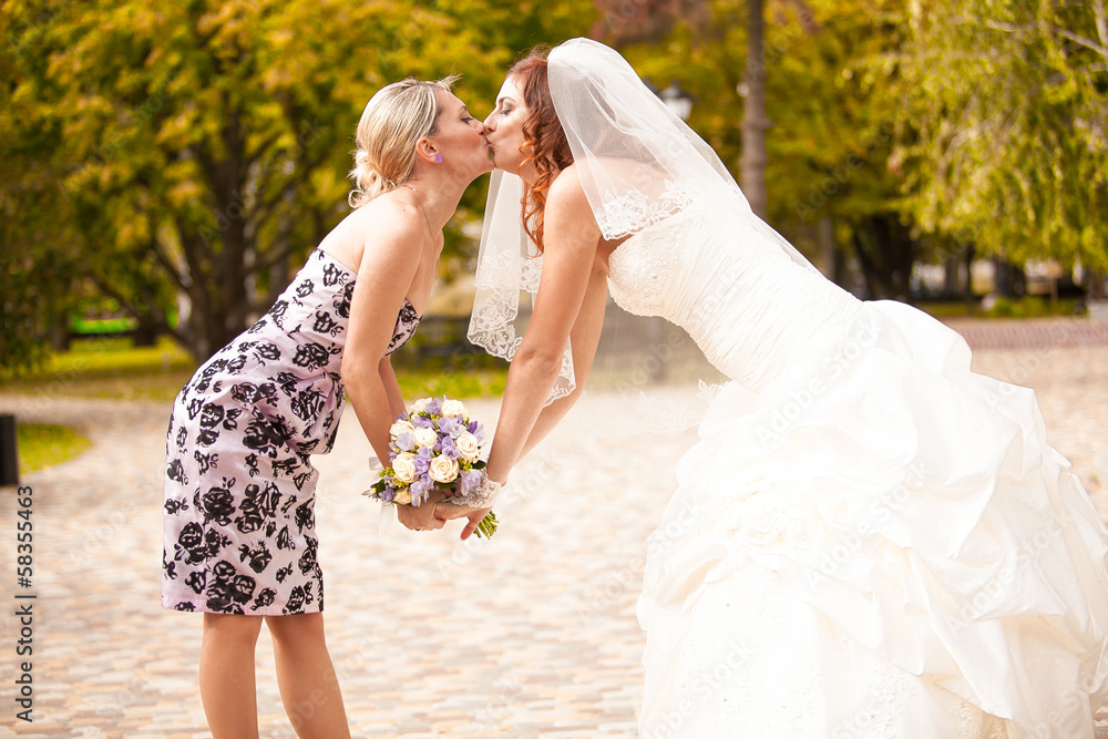 Outdoor portrait of bridesmaid kissing beautiful bride Stock Photo ...