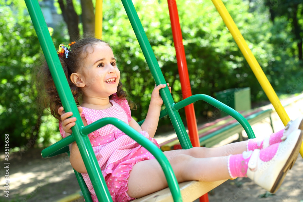 little girl in dress swinging on a swing at playground Stock Photo ...