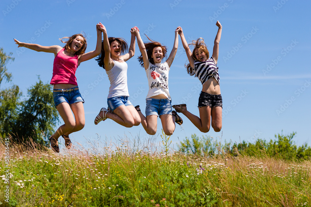 Four happy teen girls friends jumping high at blue sky Stock Photo ...
