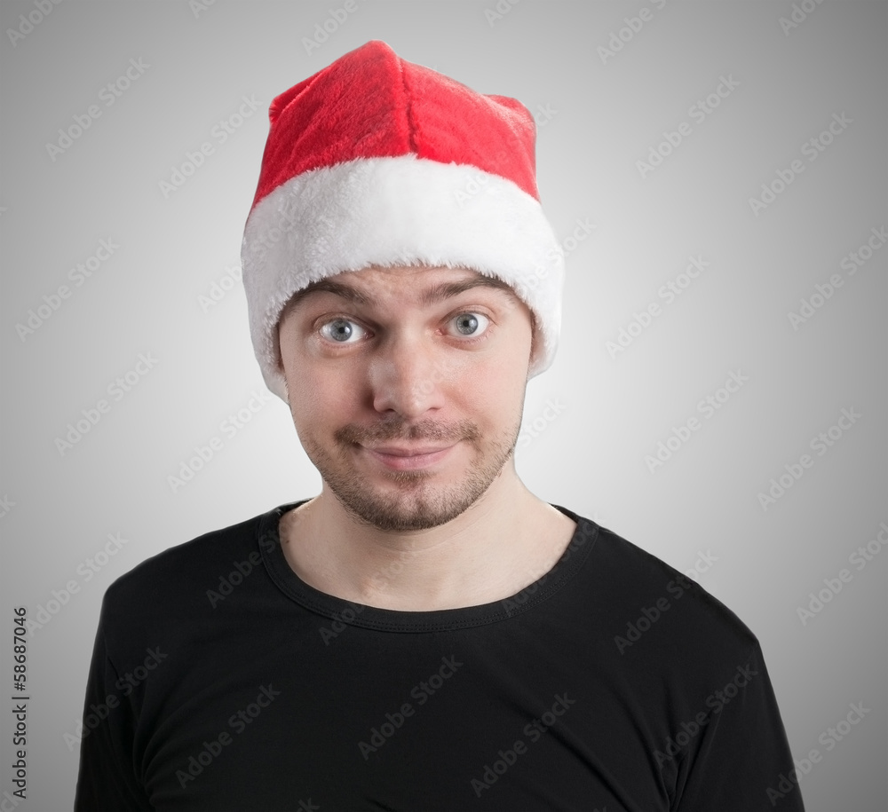 Man with a santa hat on grey background. Stock Photo | Adobe Stock