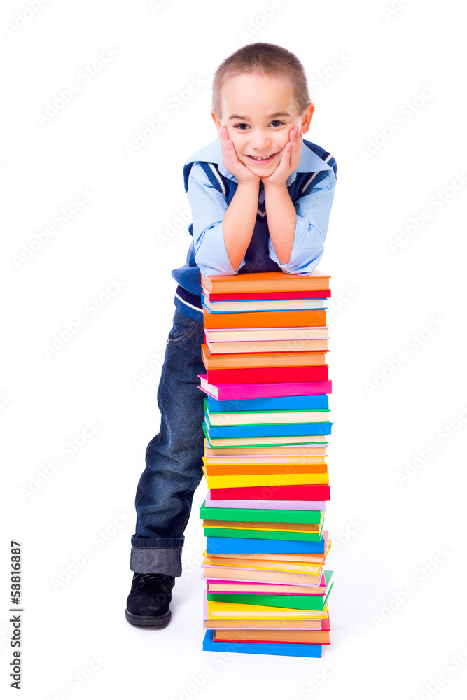 Little boy standing near stacked colorful books Stock Photo | Adobe Stock