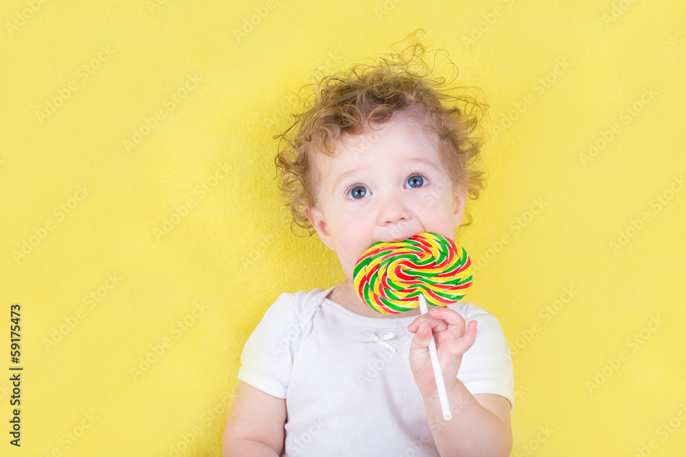 Cute funny baby girl with a big candy on yellow background Stock Photo ...
