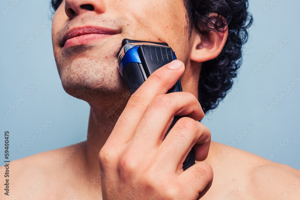 Foto Stock Man shaving with electric razor | Adobe Stock
