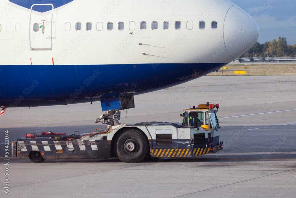 Aircraft tug towing big airliner to dock position Stock Photo | Adobe Stock