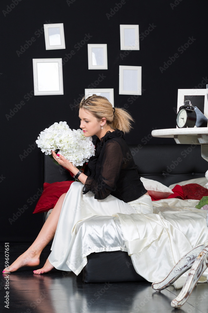 girl sitting on a bed with flowers in room with empty frame Stock Photo ...