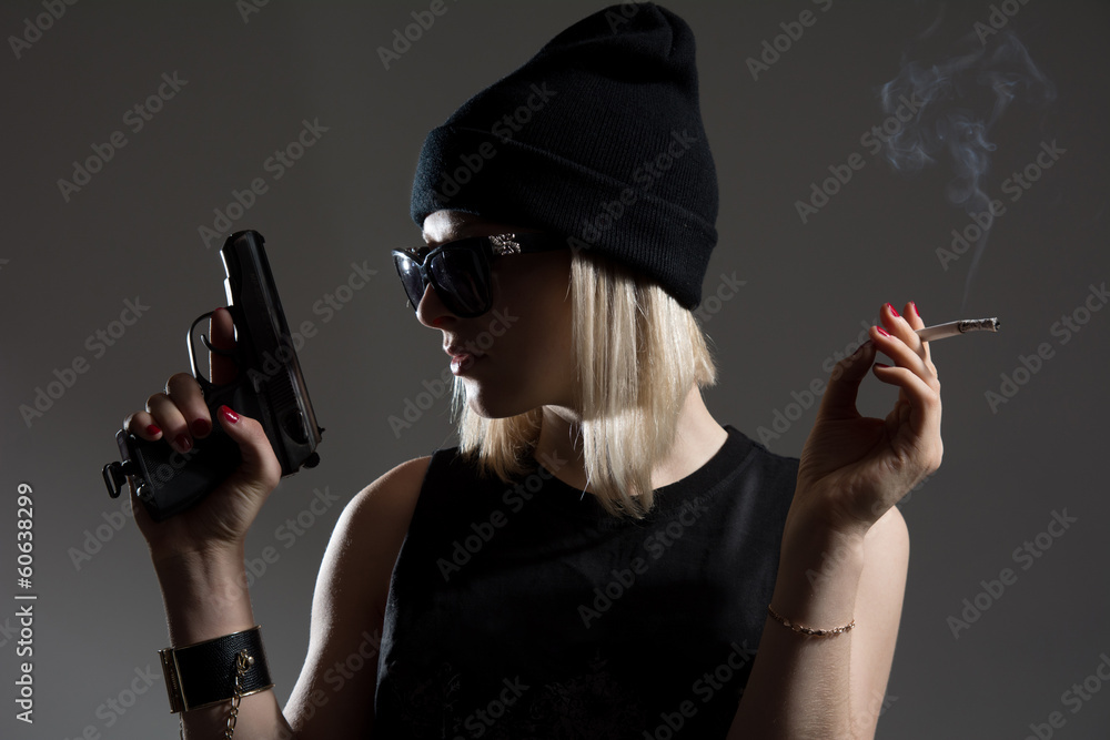 Beautiful girl with a gun in his hand and smoking a cigarette. Stock ...