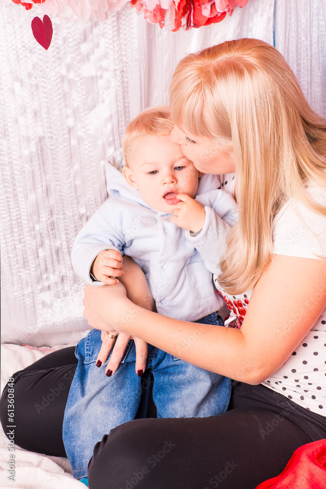 Beautiful happy mother hugging baby on a bed Stock Photo | Adobe Stock