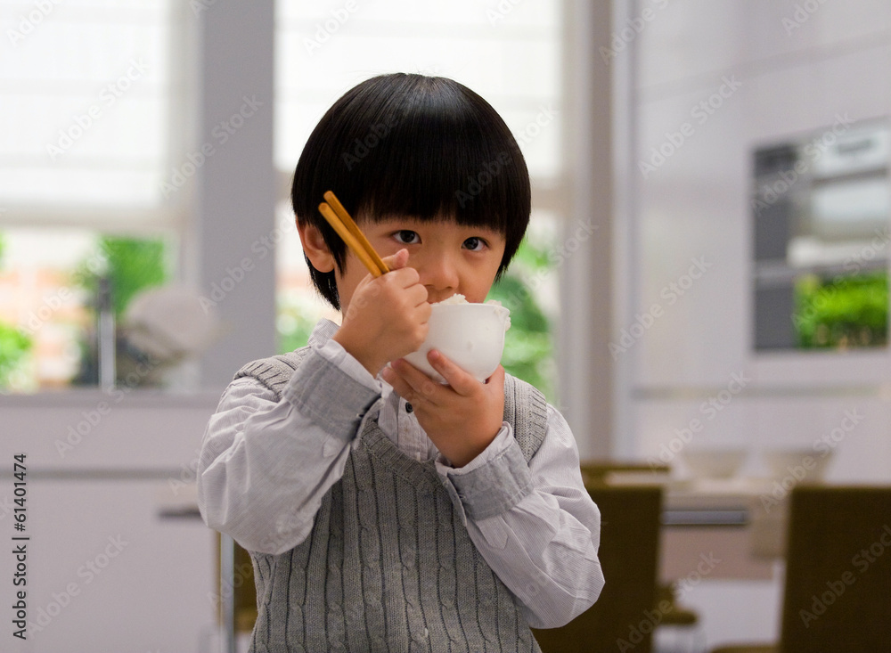 Asian boy eating rice with chopsticks Stock Photo | Adobe Stock
