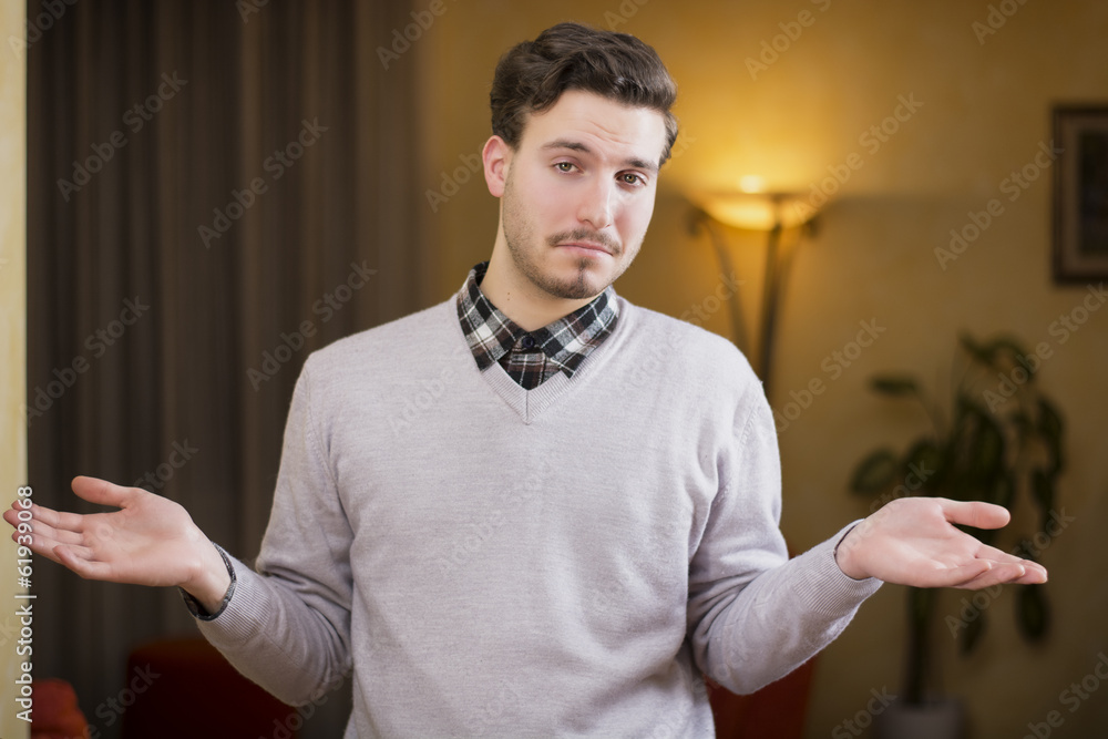 Confused or doubtful young man shrugging with palms open Stock Photo ...