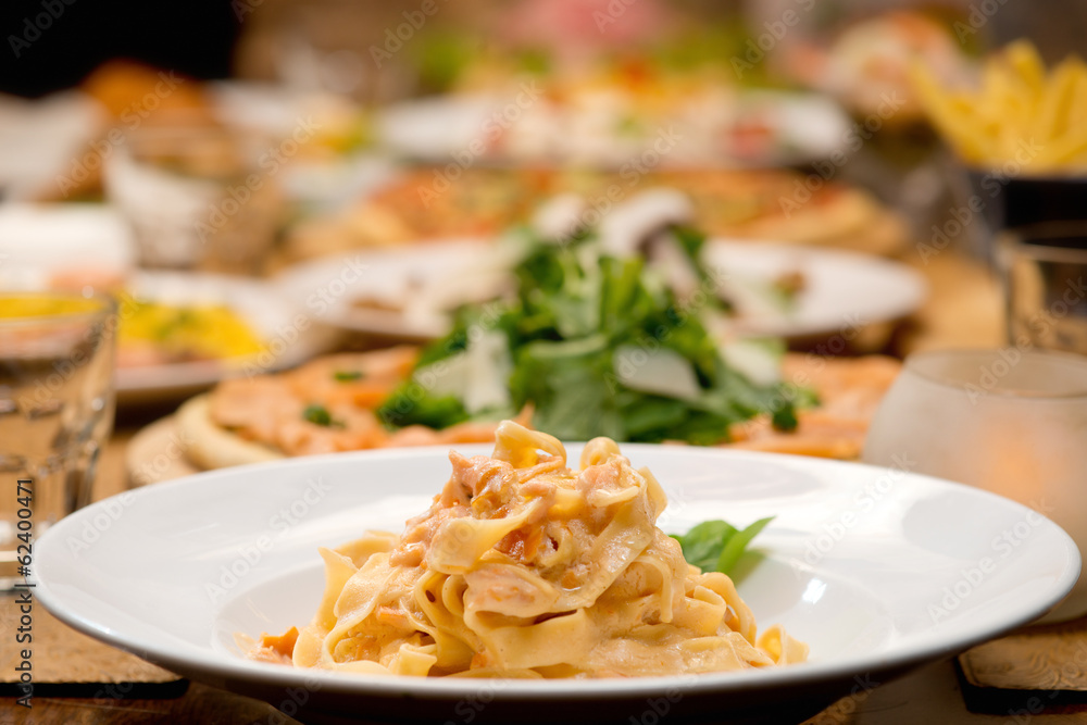 Table of pasta and other food plates in the background Stock Photo ...