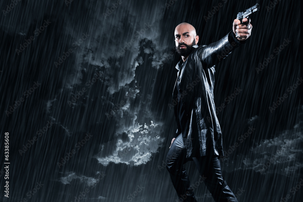 Dangerous bald gangster man with beard holding gun. Wearing blac Stock ...