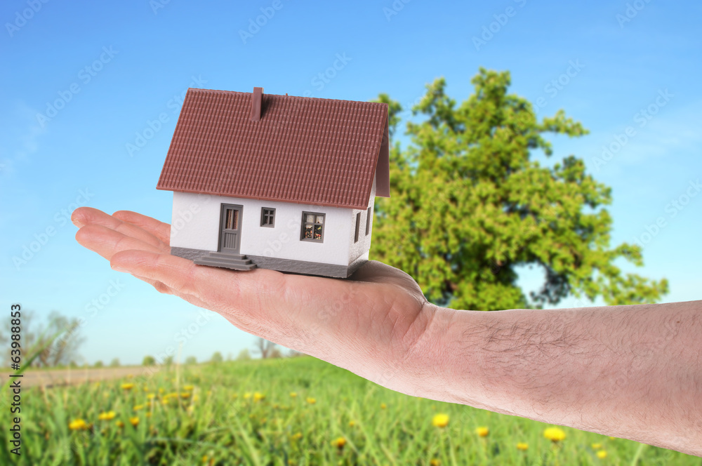 Hand hält ein kleines Haus in der Natur Stock Photo | Adobe Stock