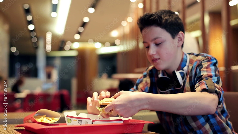 Young teenager eating tasty hamburger in fast food restaurant Stock ...