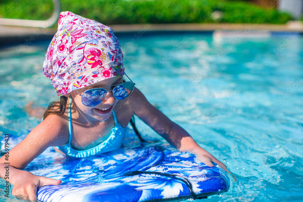 Little girl swimming on a surfboard in swimmingpoll Stock Photo | Adobe ...