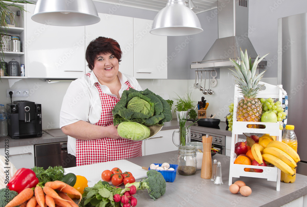 Chubby smiling woman in the kitchen making diet. Stock-Foto | Adobe Stock