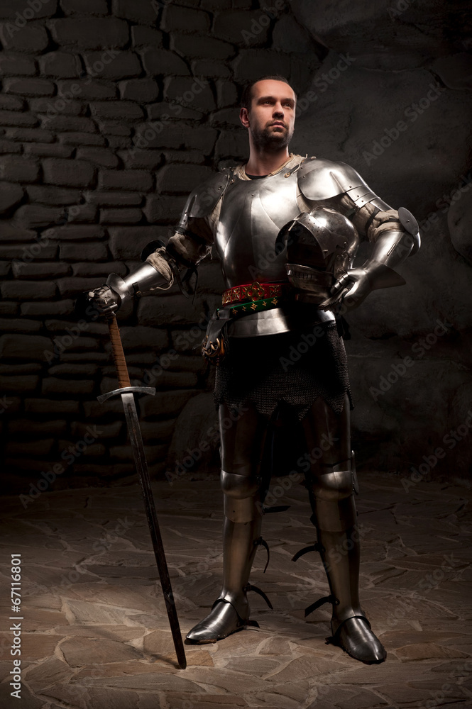 Medieval Knight posing with sword in a dark stone background Stock ...