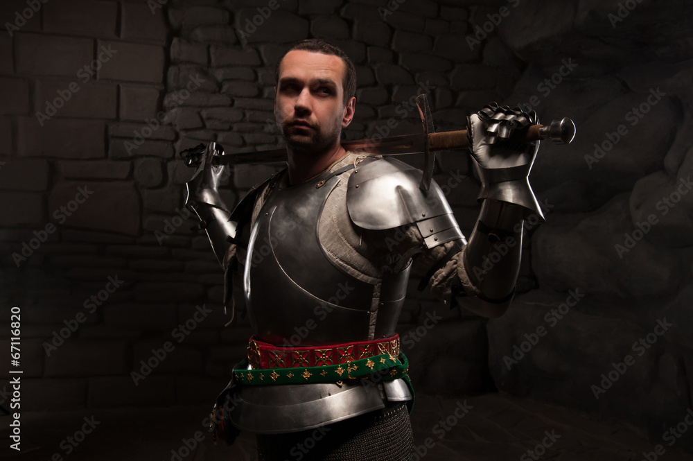 Medieval Knight posing with sword in a dark stone background Stock ...
