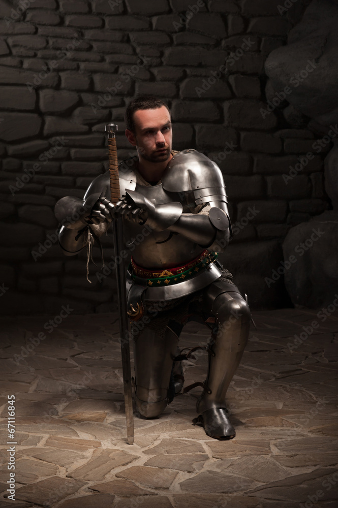 Medieval knight kneeling with sword Stock Photo | Adobe Stock