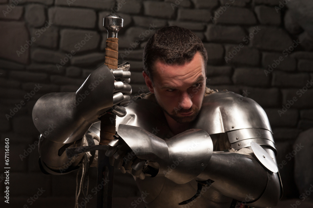 Medieval knight kneeling with sword Stock Photo | Adobe Stock