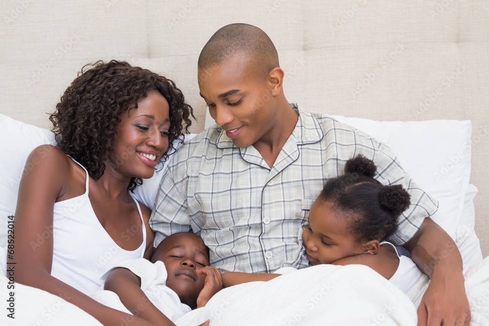 Happy family cuddling in bed together Stock-Foto | Adobe Stock