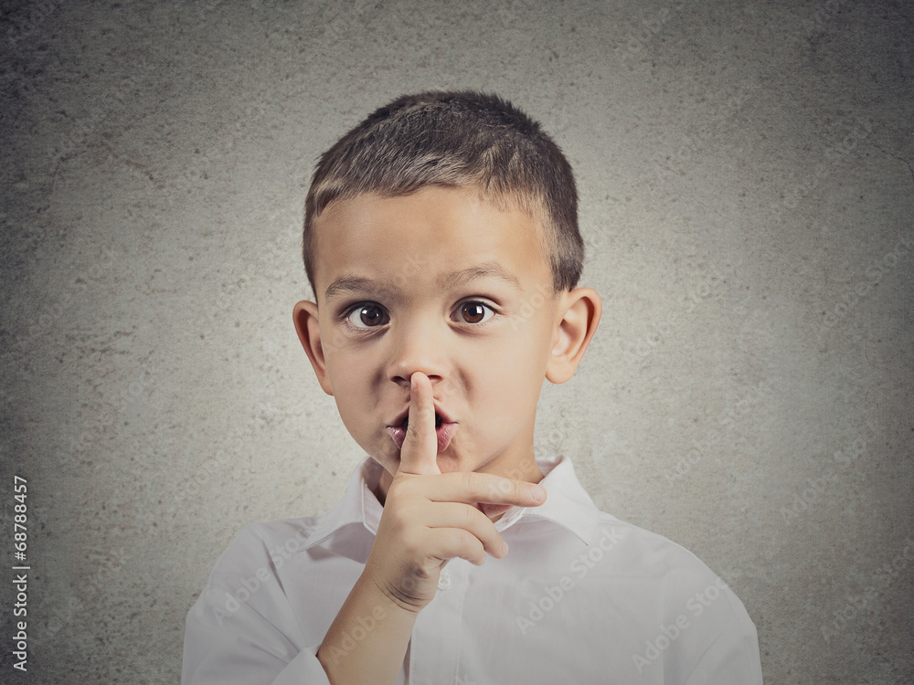 Boy placing finger on lips showing quiet gesture grey background Stock ...