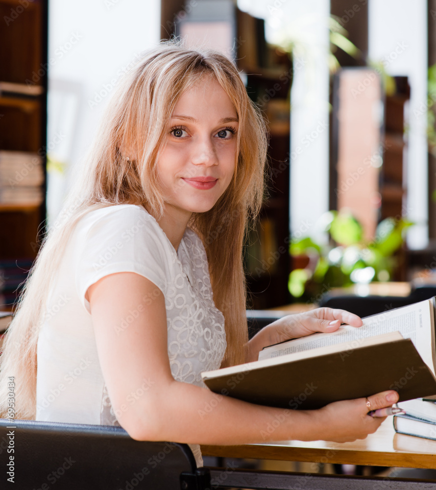 Portrait of a pretty female student studying in library with ope Stock ...