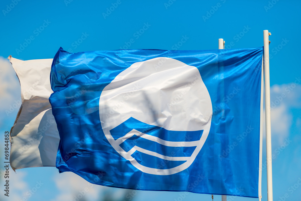 blue flag flying on the beach near the sea Stock Photo | Adobe Stock