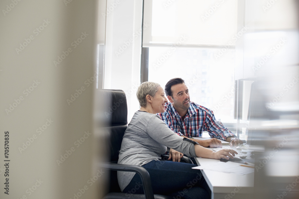 Two people, colleagues in an office looking at a computer screen. Stock ...