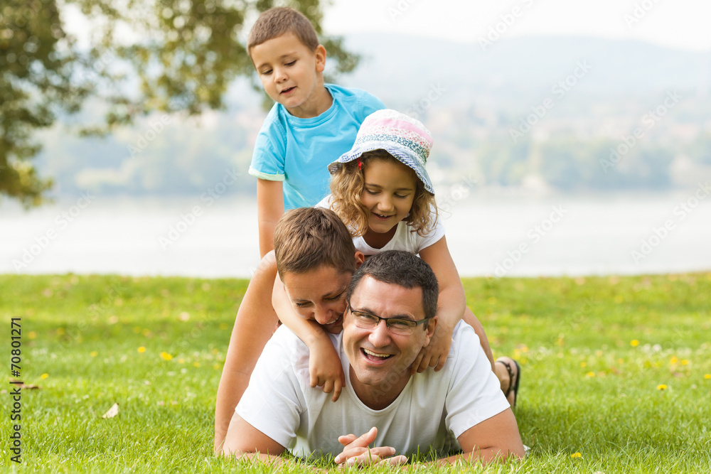 Portrait of happy family making a human pyramid in the meadow. Stock ...