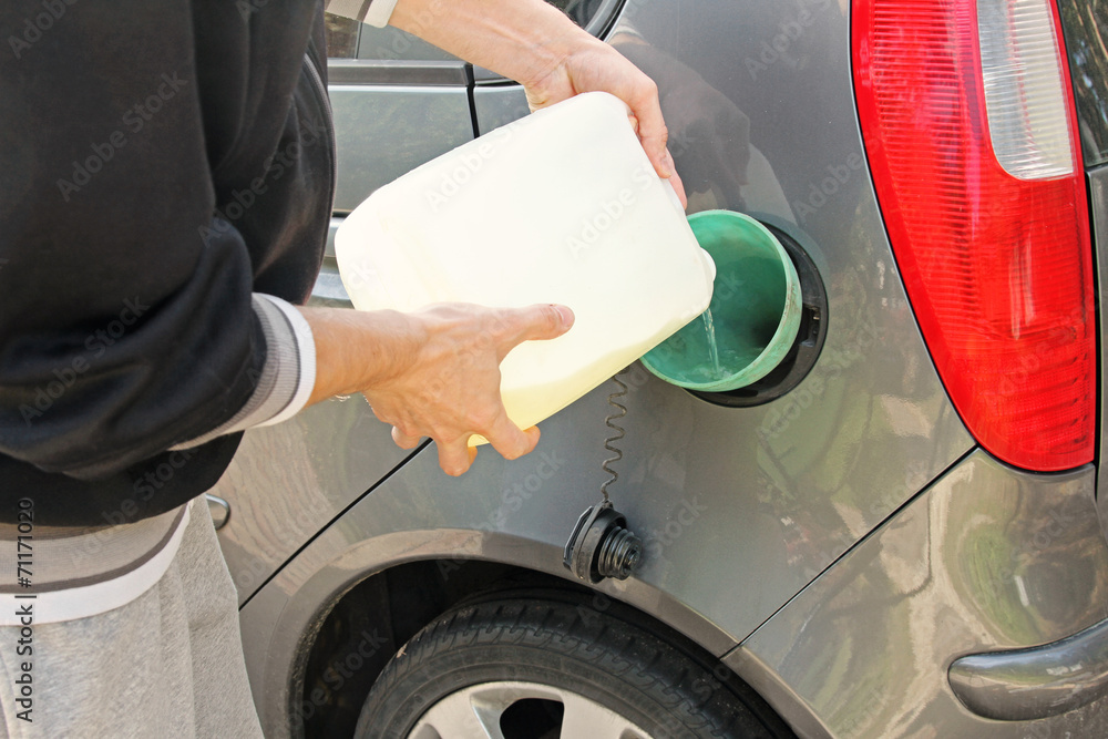 pouring gasoline into the gas tank from a white canister Stock Photo ...