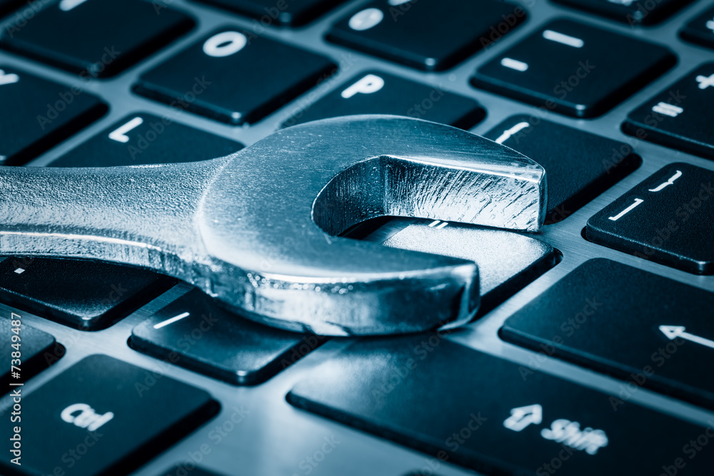 Wrench over a computer keyboard toned in blue Stock Photo | Adobe Stock
